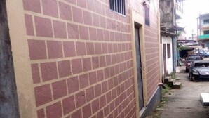 Um beco estreito, com uma parede de tijolos em um lado e um passeio de concreto.