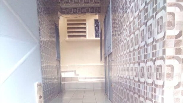 Um corredor estreito com piso de azulejos e paredes estampadas.