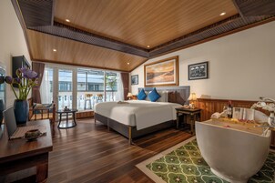 Quarto espaçoso com cama grande, área de estar com laptop, banheira e vista para o exterior.