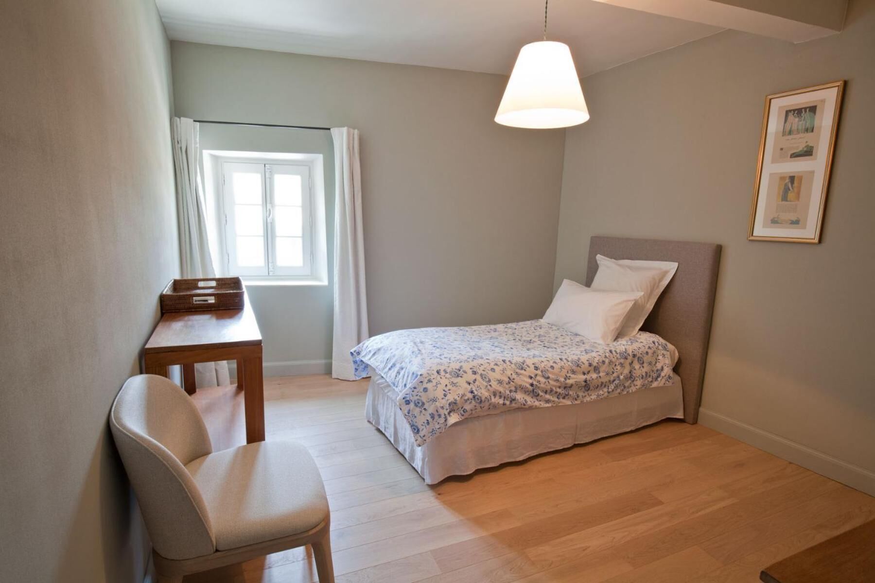 Um quarto com uma cama, uma escrivaninha e uma cadeira.