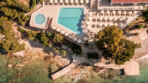 Vista aérea de um resort com uma grande piscina, espreguiçadeiras e área de praia.