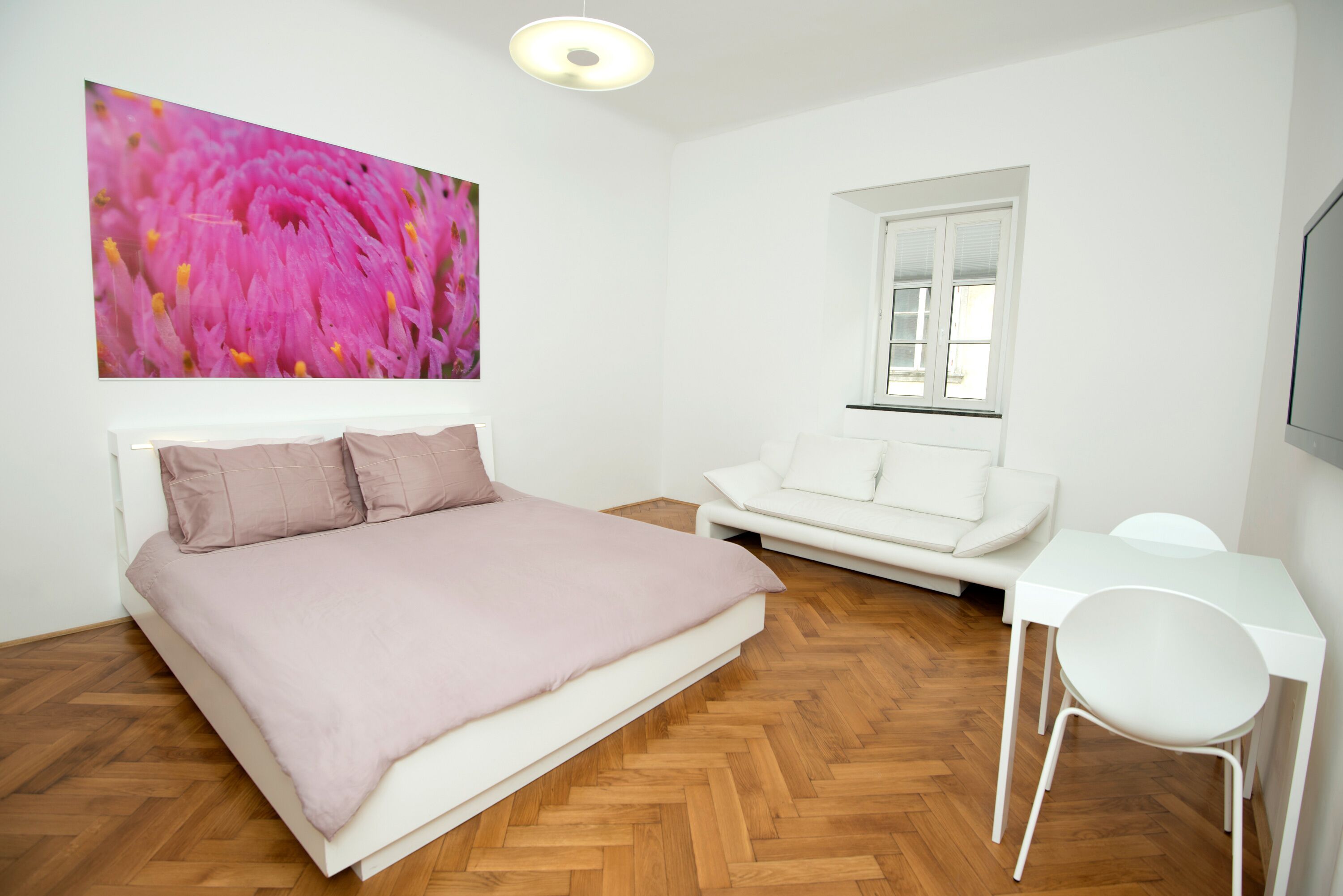 Um quarto com uma cama, um sofá branco, uma mesinha e uma cadeira.
