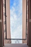 Uma varanda com grade de metal e vista para o céu.