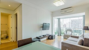 Uma sala de estar moderna com televisão de tela plana, mesa de jantar e sofá.
