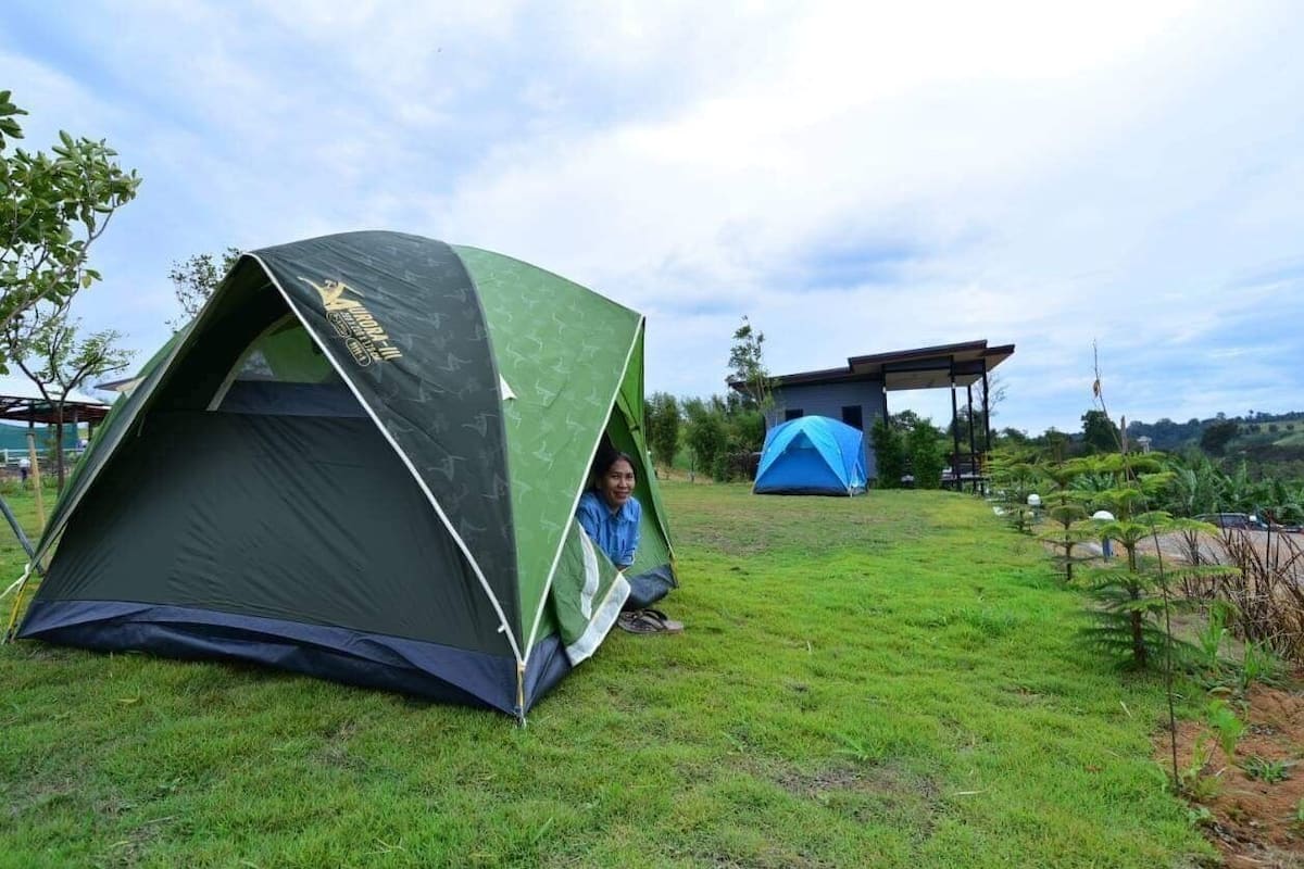 Tenda montada em um campo gramado com uma pessoa lá dentro.