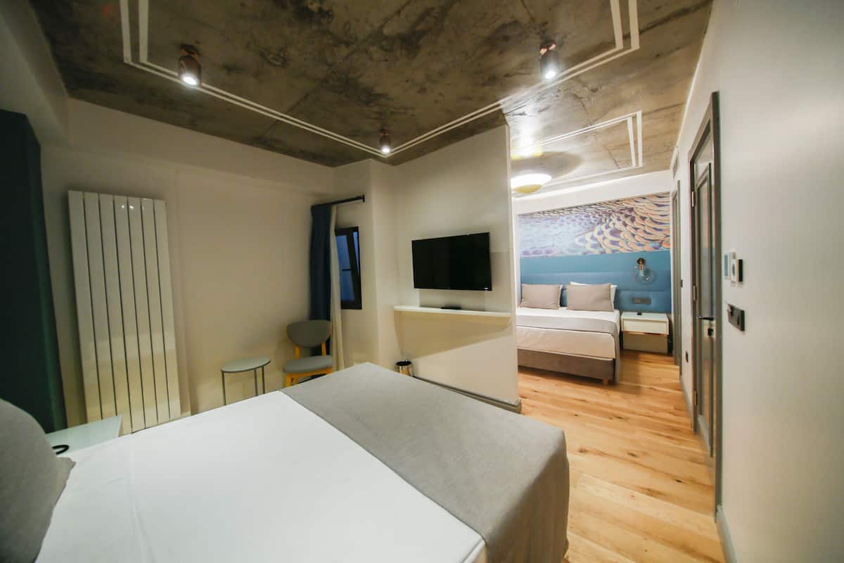 Quarto de hotel com cama, televisão, mesa pequena e uma cadeira.