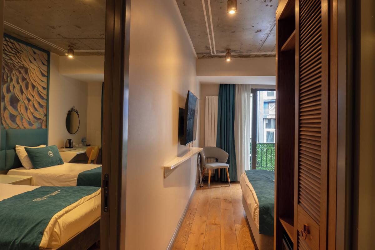 Quarto de hotel com duas camas, televisão, escrivaninha e cadeira.