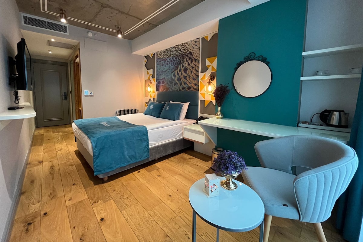 Quarto moderno com cama, mesa de cabeceira, cadeira e uma pequena mesa redonda com um vaso.