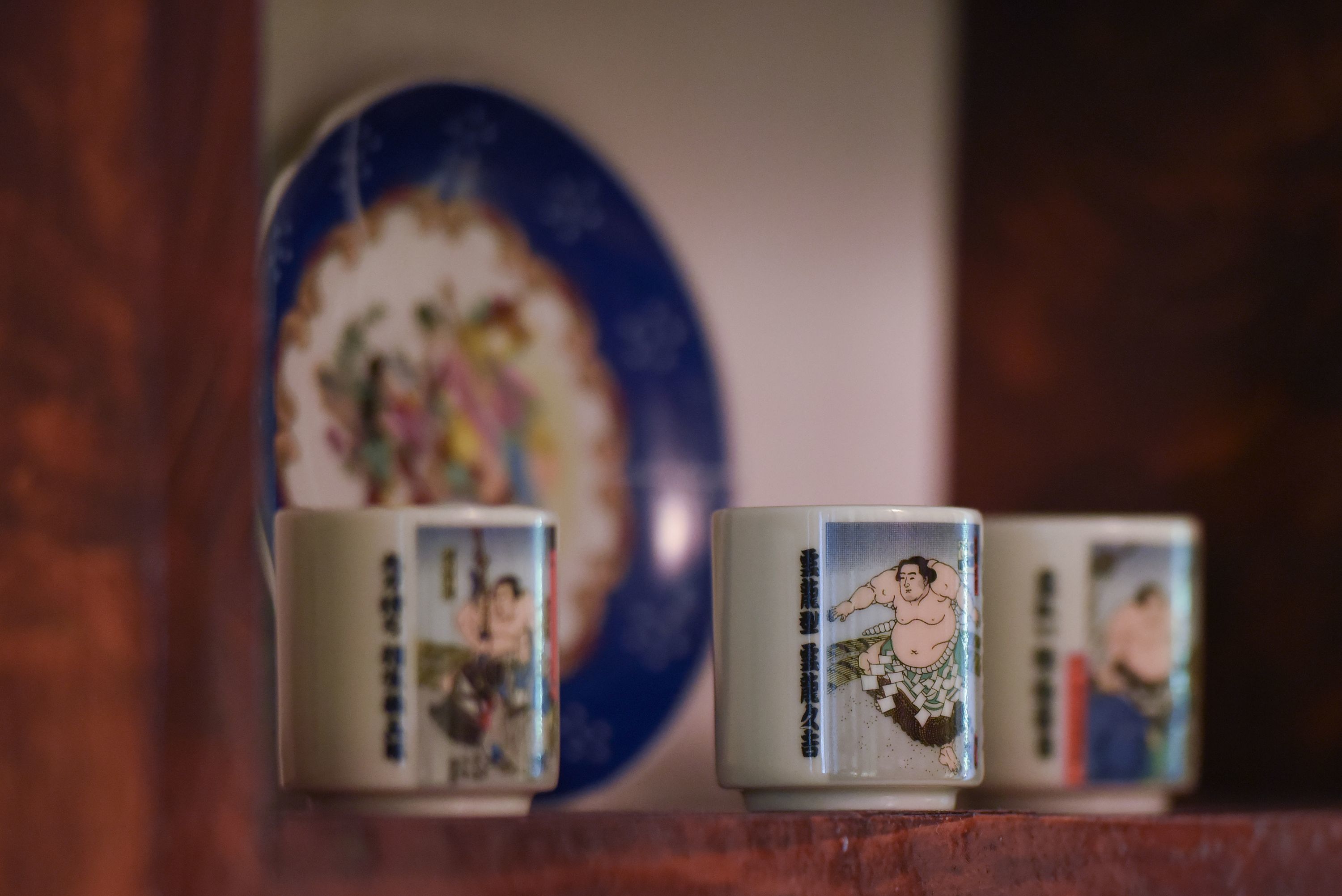 Duas chávenas de cerâmica com motivos artísticos japoneses sobre uma superfície de madeira.