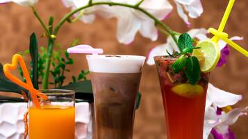 Três bebidas sobre uma mesa, com um vaso de flores brancas ao fundo.