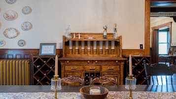 Uma área de refeições com um aparador de madeira, uma adega e uma mesa posta com uma vela e taças.