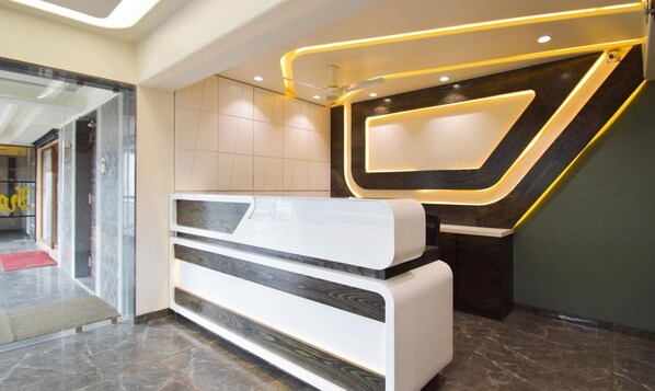 Uma receção com design moderno, combinando acabamentos em branco e madeira escura.