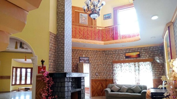 Uma sala de estar ampla com lareira, um sofá e uma escada que leva a um andar superior.