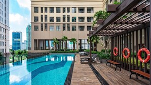 Piscina com deck de madeira, bancos e boias salva-vidas.