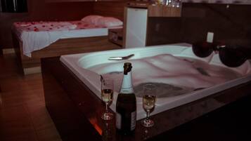 Quarto com hidromassagem, duas taças de vinho e uma garrafa de champanhe.
