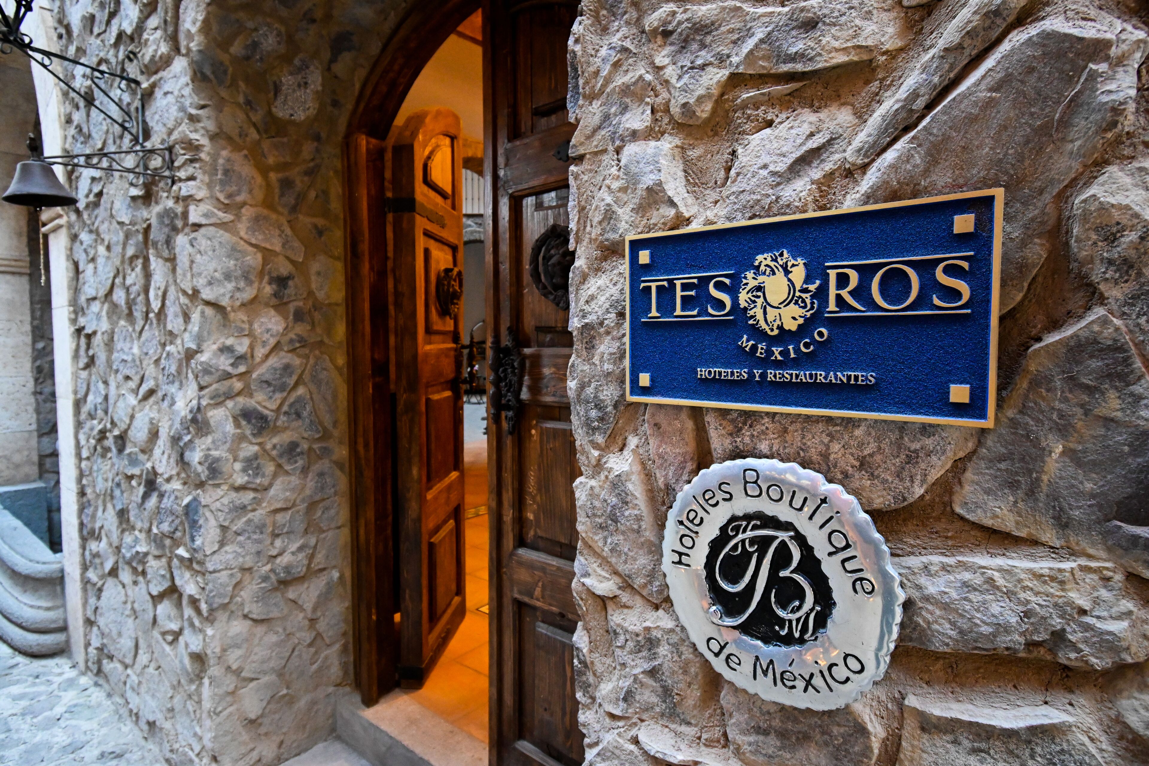 Um muro de pedra com uma placa para o hotel e restaurante 'TES ROS', e uma etiqueta para 'Hofele Boutique de Mexico'.