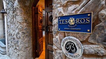 Um muro de pedra com uma placa para o hotel e restaurante 'TES ROS', e uma etiqueta para 'Hofele Boutique de Mexico'.