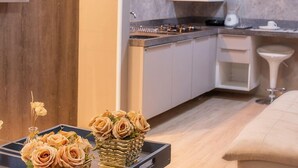 Cozinha moderna com armários brancos, micro-ondas e pia. Há um vaso com flores na bancada.