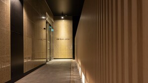 Um corredor com uma placa indicando "KIKYO EX INN" e design moderno, paredes revestidas de azulejos e um painel decorativo na parede da direita.