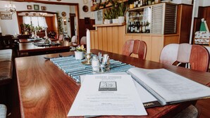 Uma mesa de jantar de madeira com um menu, uma vela e um jogo americano.