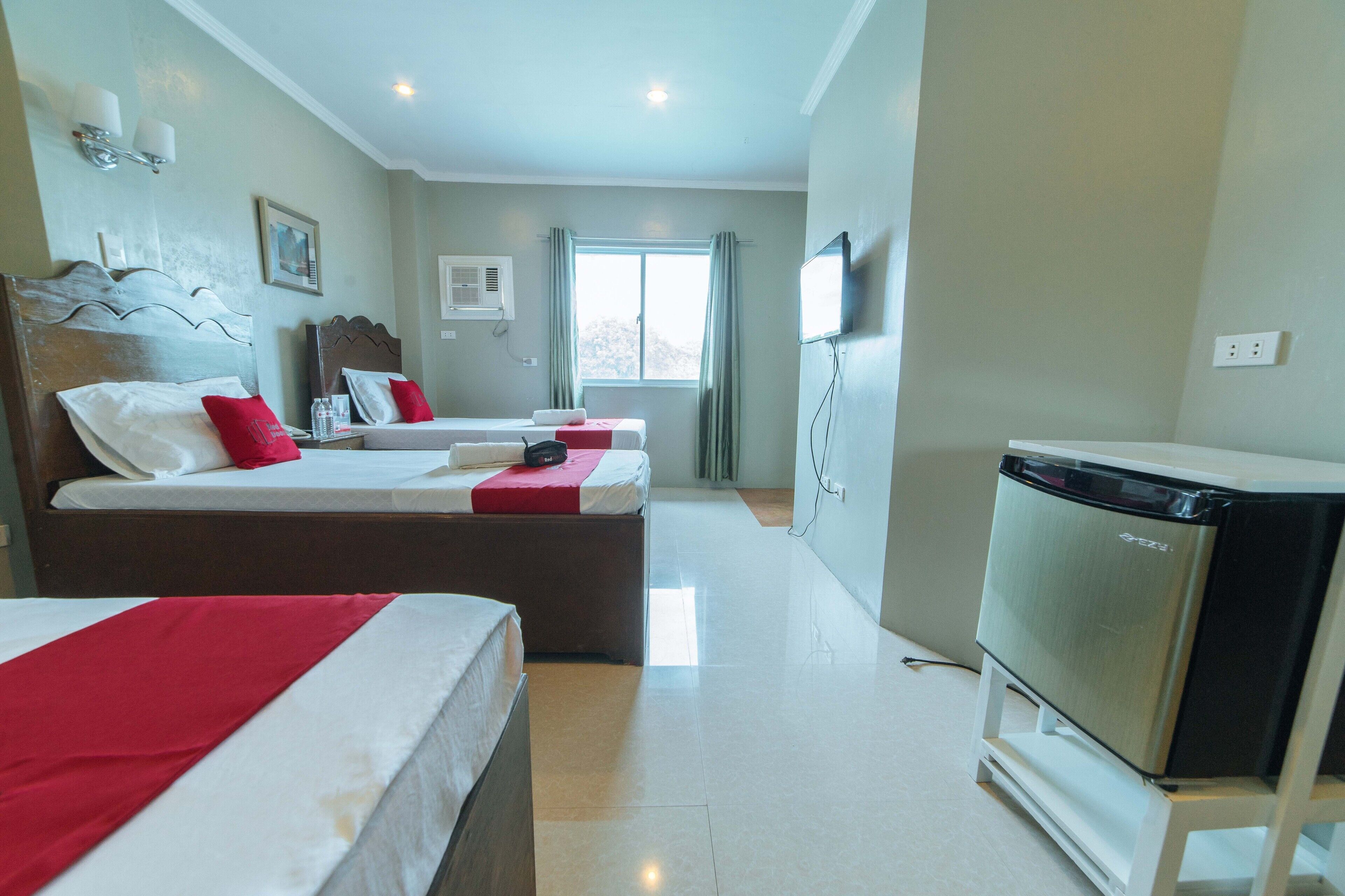 Quarto de hotel com duas camas, televisão e minibar.