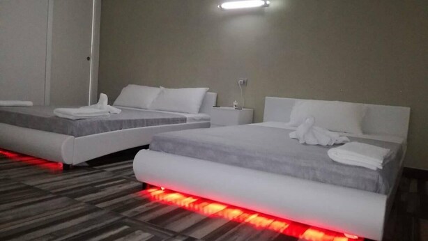 Quarto de hotel com duas camas, uma mesa de cabeceira e uma luminária fixada na parede.