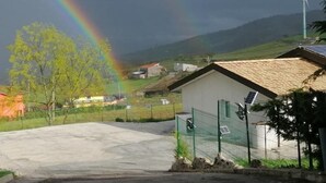 Um cenário rural com uma casa, uma área cercada e uma vista distante de montanhas.