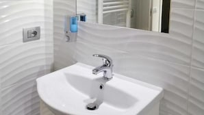 Casa de banho moderna com lavatório branco, um espelho grande e um porta-toalhas.
