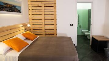 Quarto com cabeceira de madeira, cama com almofadas laranja, colcha marrom e mesa de cabeceira.