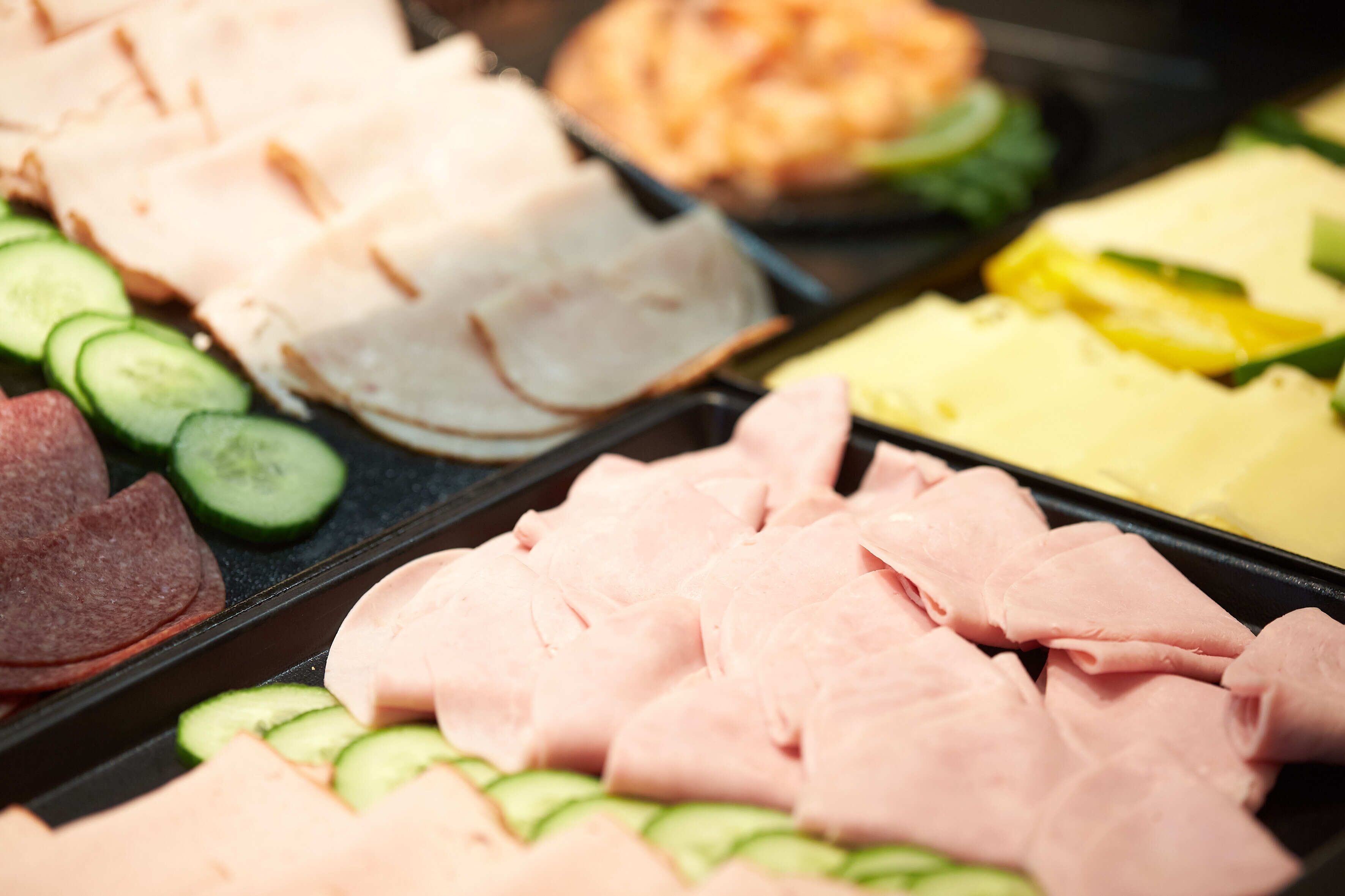 Diversos tipos de carnes fatiadas e queijos em uma bandeja.