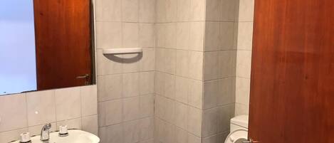 Casa de banho com lavatório branco, espelho e sanita.