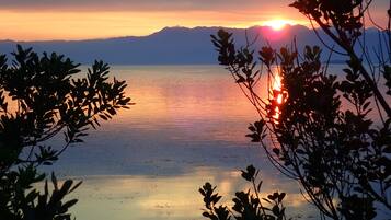 Um pôr do sol sobre águas calmas, com montanhas ao fundo.