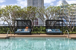 Área de piscina no terraço com duas espreguiçadeiras e vista para o horizonte da cidade.