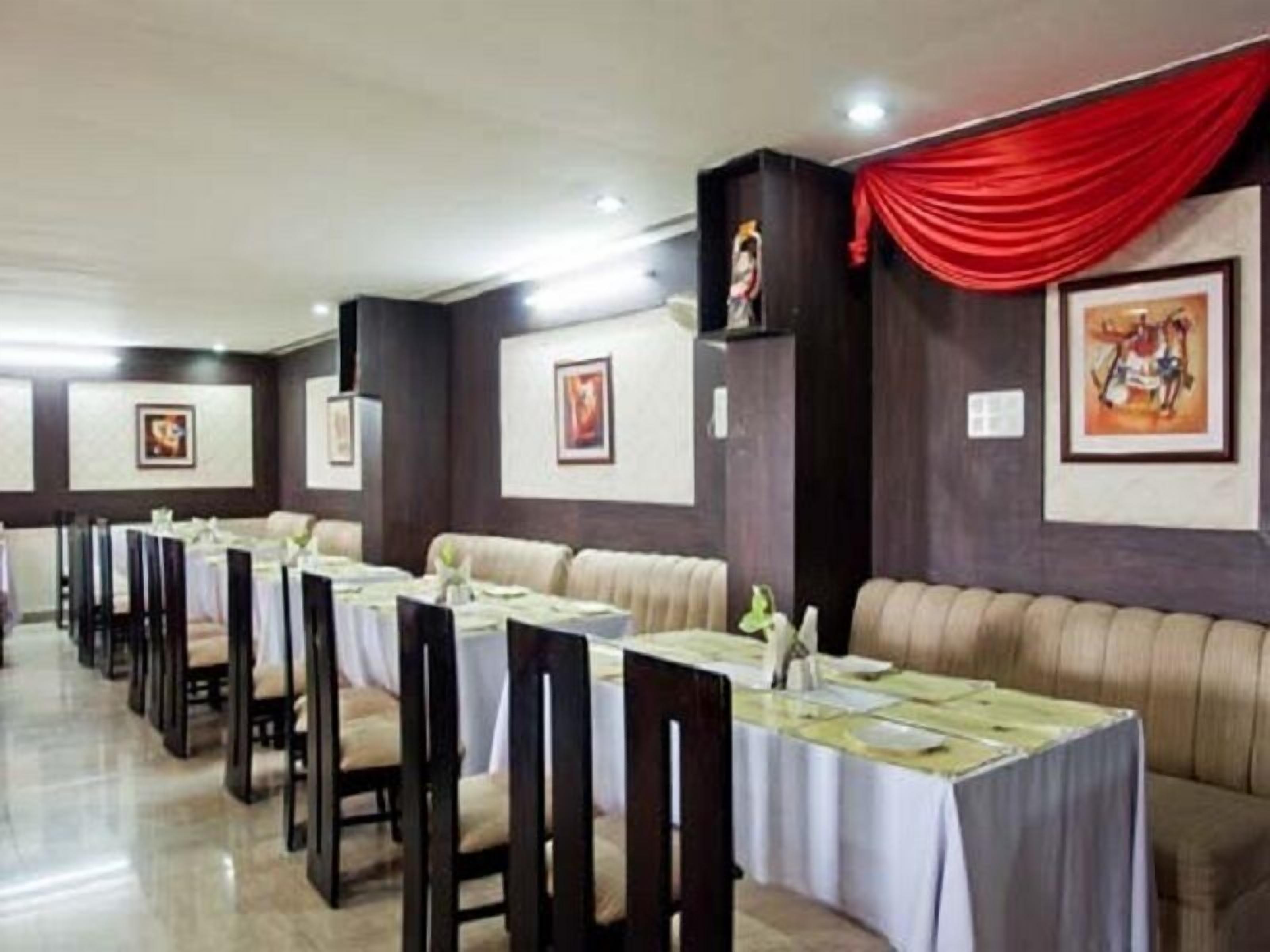 Um restaurante com várias mesas e cabines, cada uma com toalhas brancas e cadeiras escuras.