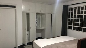 Quarto com cama, guarda-roupa e janela com padrão quadriculado.