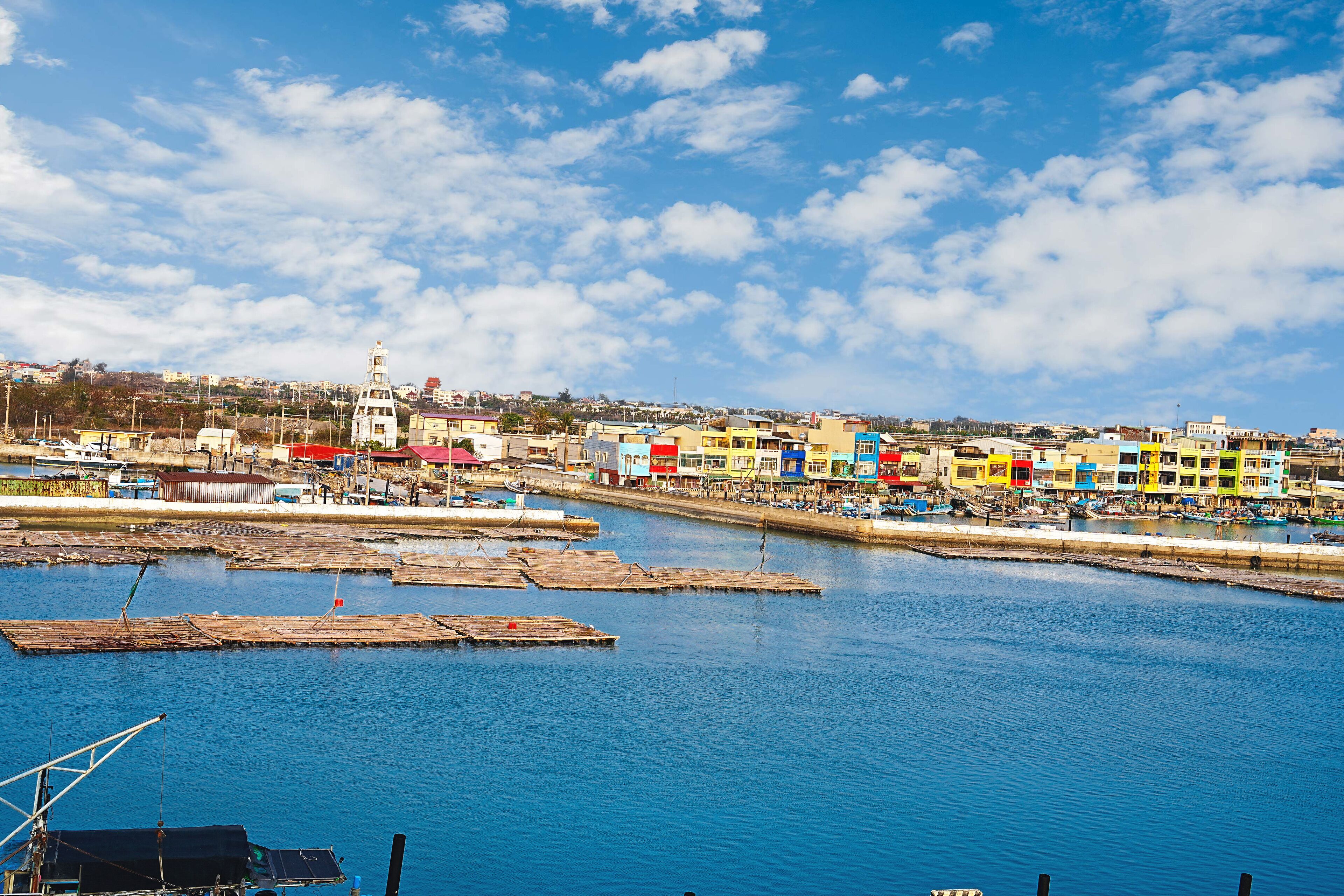 Uma área à beira-mar com edifícios coloridos, docas e céu claro.