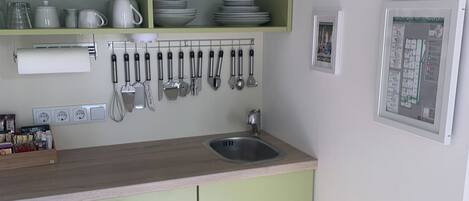 Uma cozinha com micro-ondas, chaleira e diversos utensílios pendurados na parede.