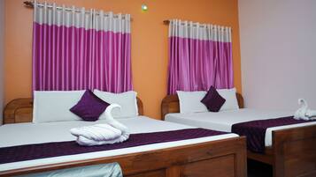Quarto de hotel com duas camas, cada uma com cabeceira de madeira, roupa de cama branca, almofadas roxas e manta roxa.
