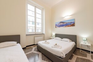 Quarto de hotel com uma cama grande, duas mesas de cabeceira, uma janela e um quadro na parede.