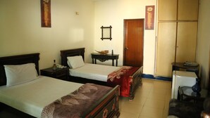 Quarto de hotel com duas camas, um guarda-roupa, uma escrivaninha e uma cadeira.