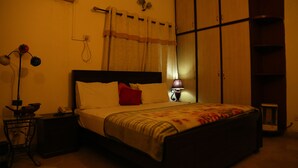 Quarto com cama, mesa de cabeceira, abajur e guarda-roupa.