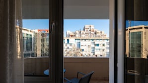 Varanda com vista para a paisagem urbana, uma cadeira e uma mesa.