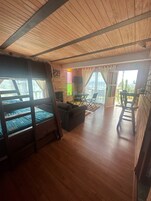 Um quarto aconchegante com uma cama beliche, um sofá, uma TV e um espaço de refeições com mesa e cadeiras.