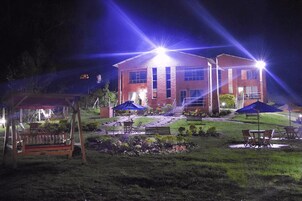 Um edifício com fachada de tijolos, várias janelas e uma área externa bem iluminada com assentos e guarda-sóis.
