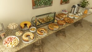 Uma mesa de buffet com diversos pães e doces.
