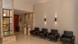 Um lobby moderno com uma receção, área de estar e uma planta decorativa.