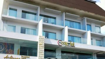 Um hotel com design moderno, com destaque para a placa do 'The Capital Hotel & Resort' e um restaurante 'Gin Sushi'.
