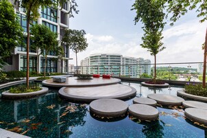 Uma área de piscina no terraço com assentos circulares e vista para um edifício moderno ao fundo.