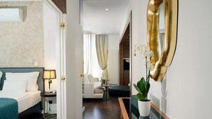 Quarto de hotel com cama, mesa de cabeceira, abajur e planta em vaso.