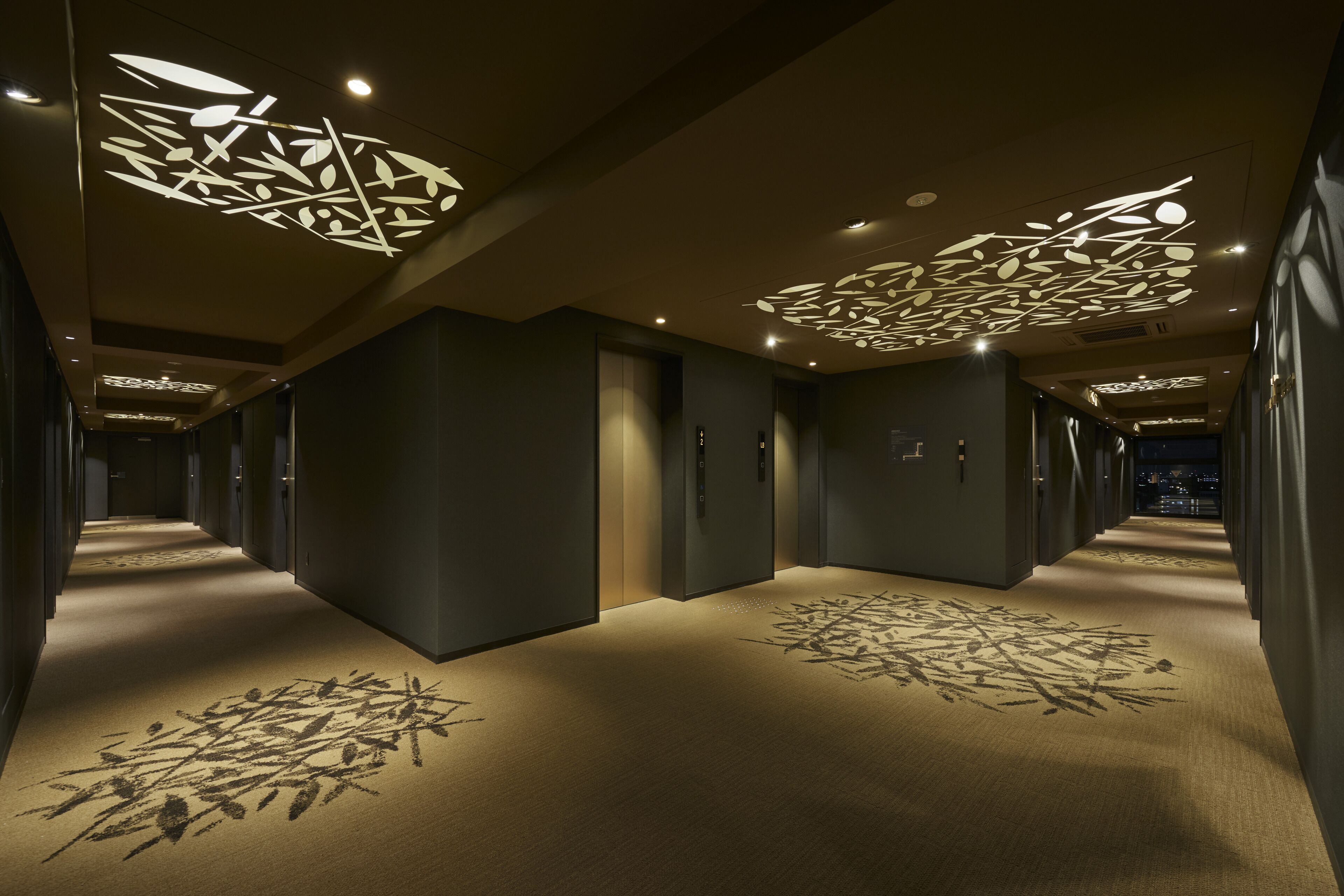 Corredor moderno de hotel, com iluminação embutida e carpete estampado.
